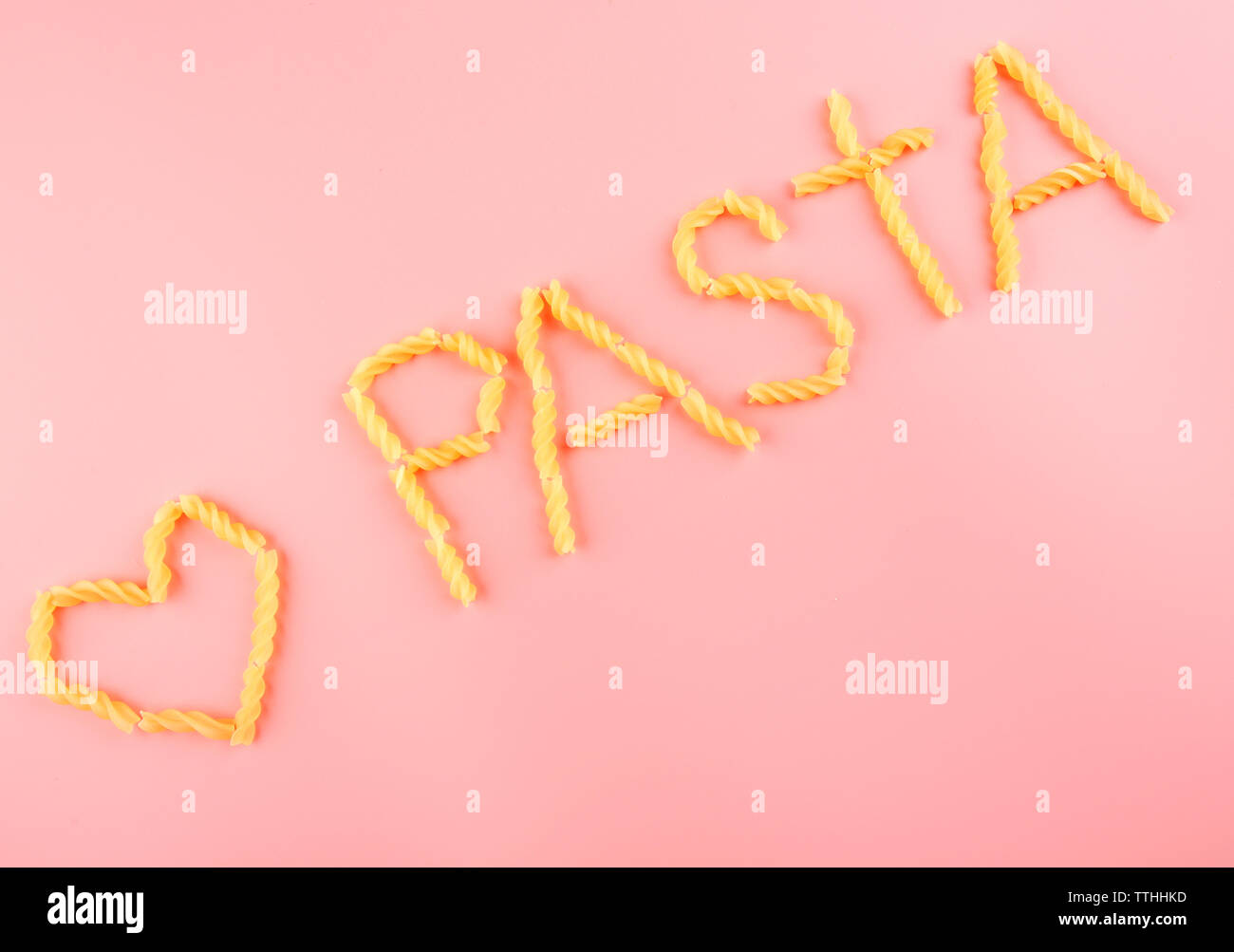 Pasta word made with fusilli on pink background Stock Photo - Alamy