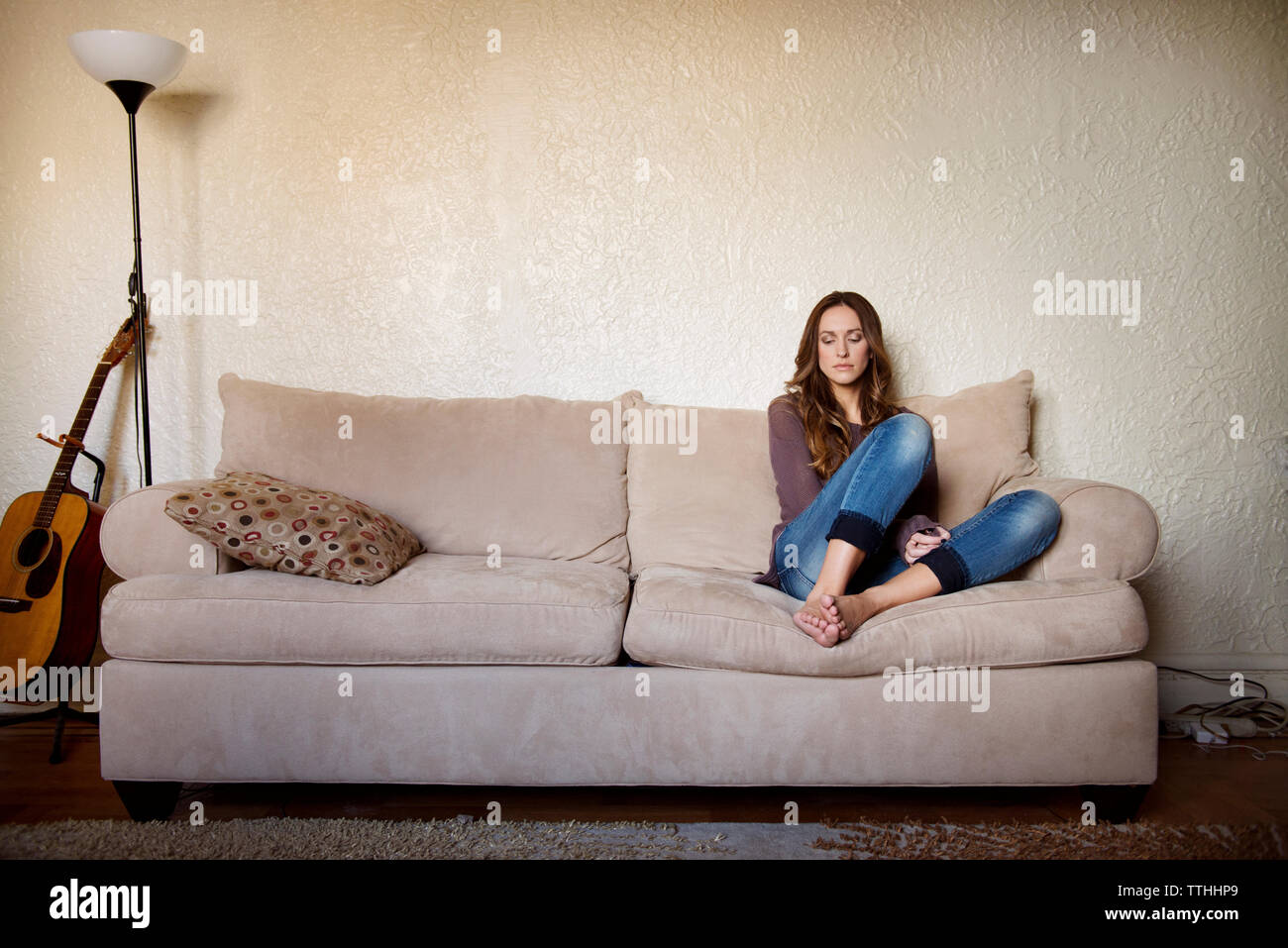 Upset woman sitting on sofa at home Stock Photo - Alamy