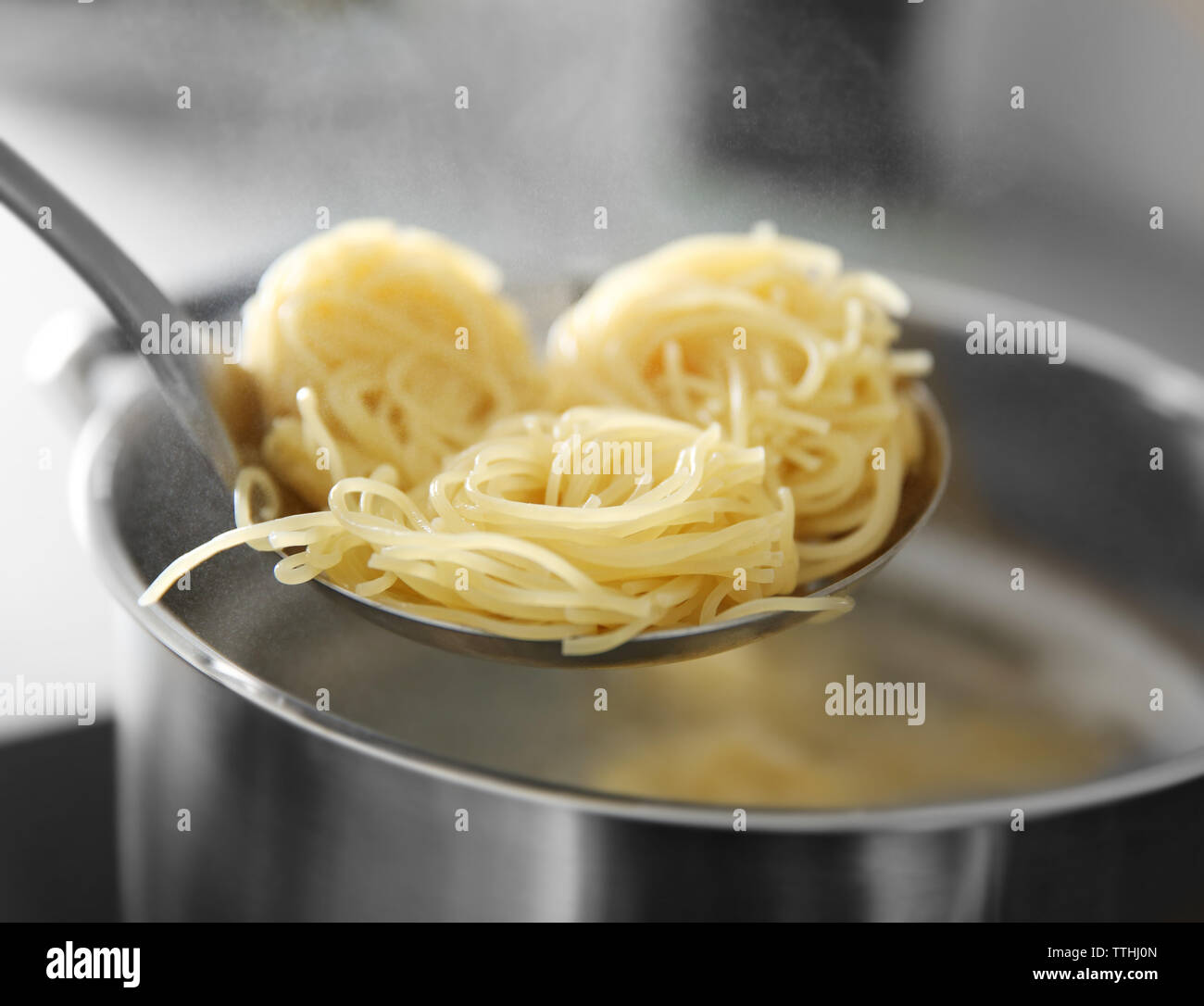 Spaghetti in strainer over the pan on stove closeup Stock Photo - Alamy