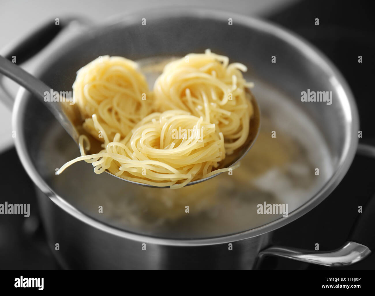Spaghetti in strainer over the pan on stove closeup Stock Photo - Alamy