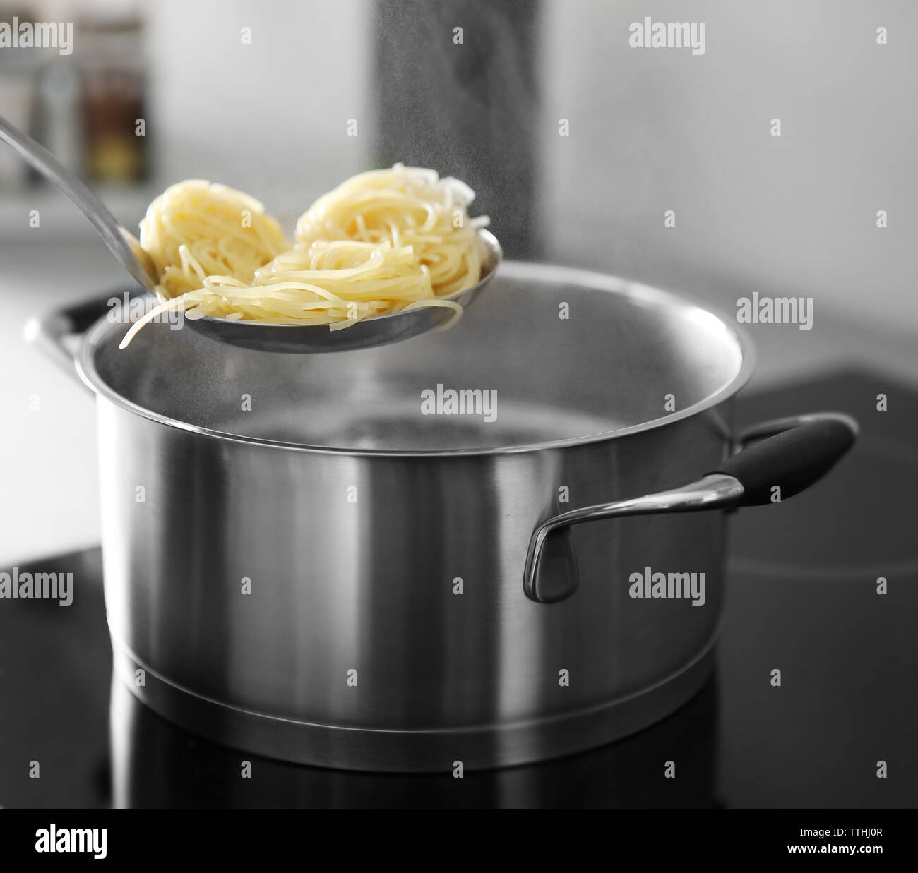 Spaghetti in strainer over the pan on stove closeup Stock Photo - Alamy