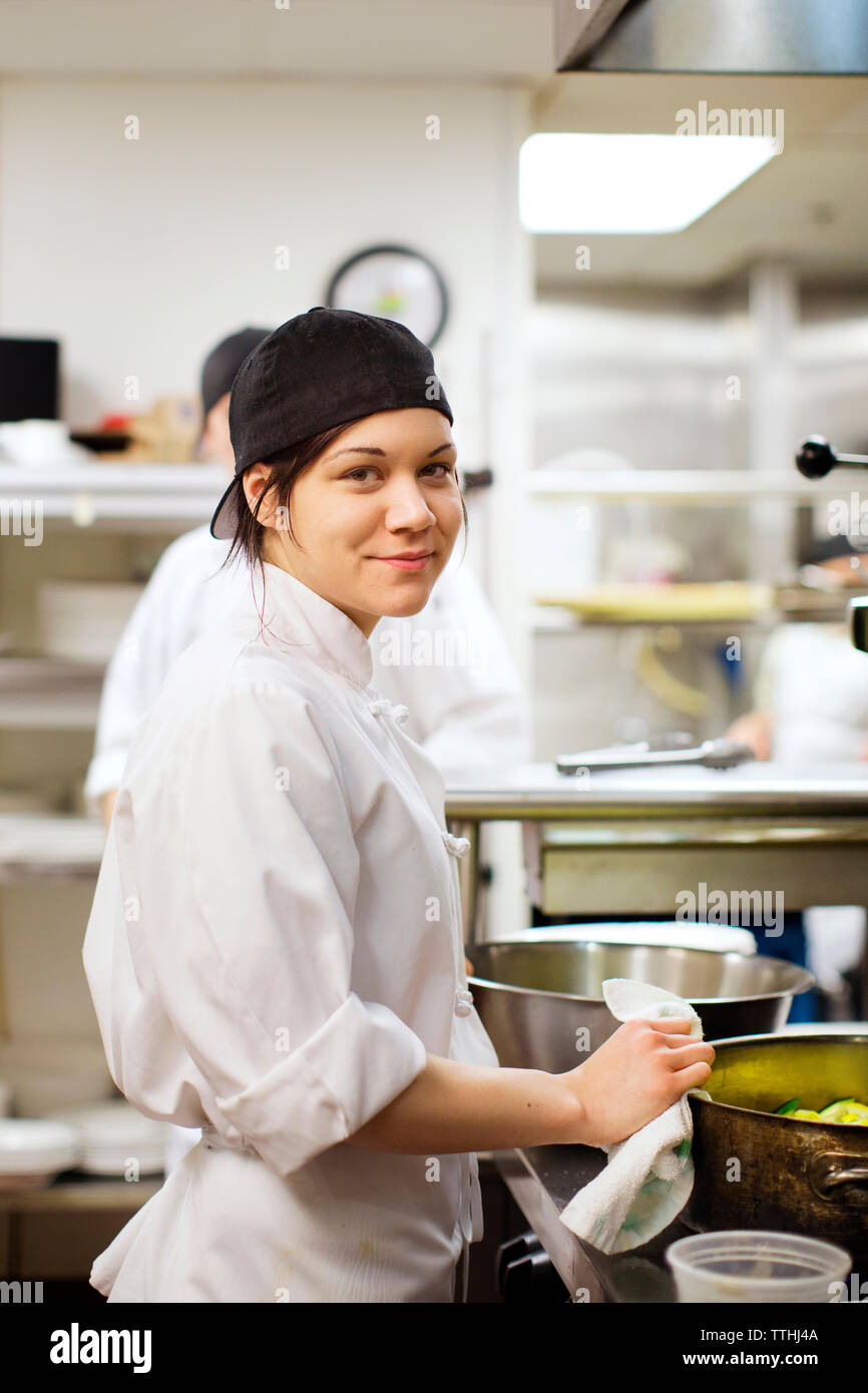 Portrait of happy female chef preparing food in commercial kitchen ...