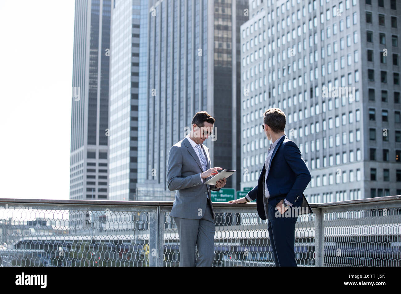 businessman using tablet computer while standing friend against city ...