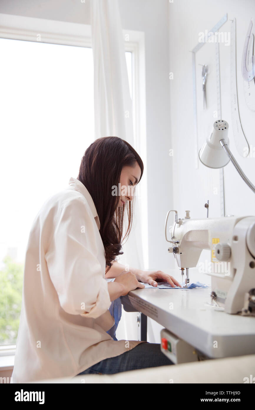 Side view of fashion designer using sewing machine in studio Stock ...