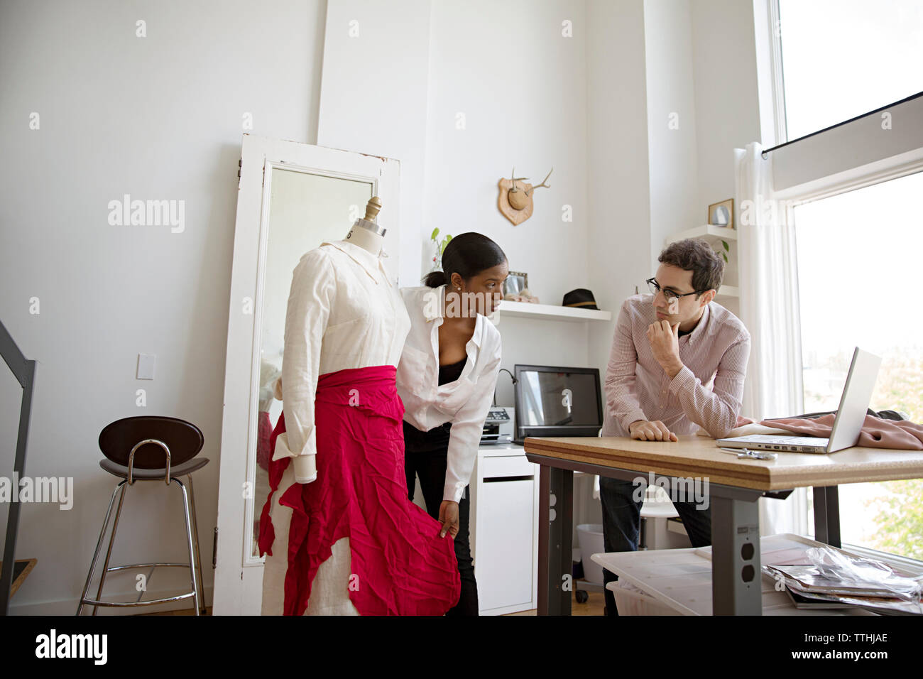 Fashion designer showing dress on model to colleague Stock Photo - Alamy