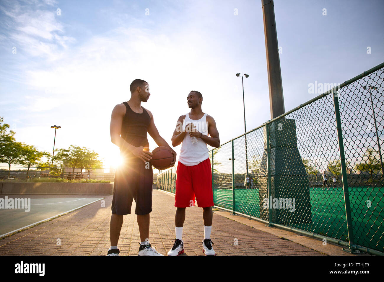 Friends talking while standing in basketball court Stock Photo - Alamy