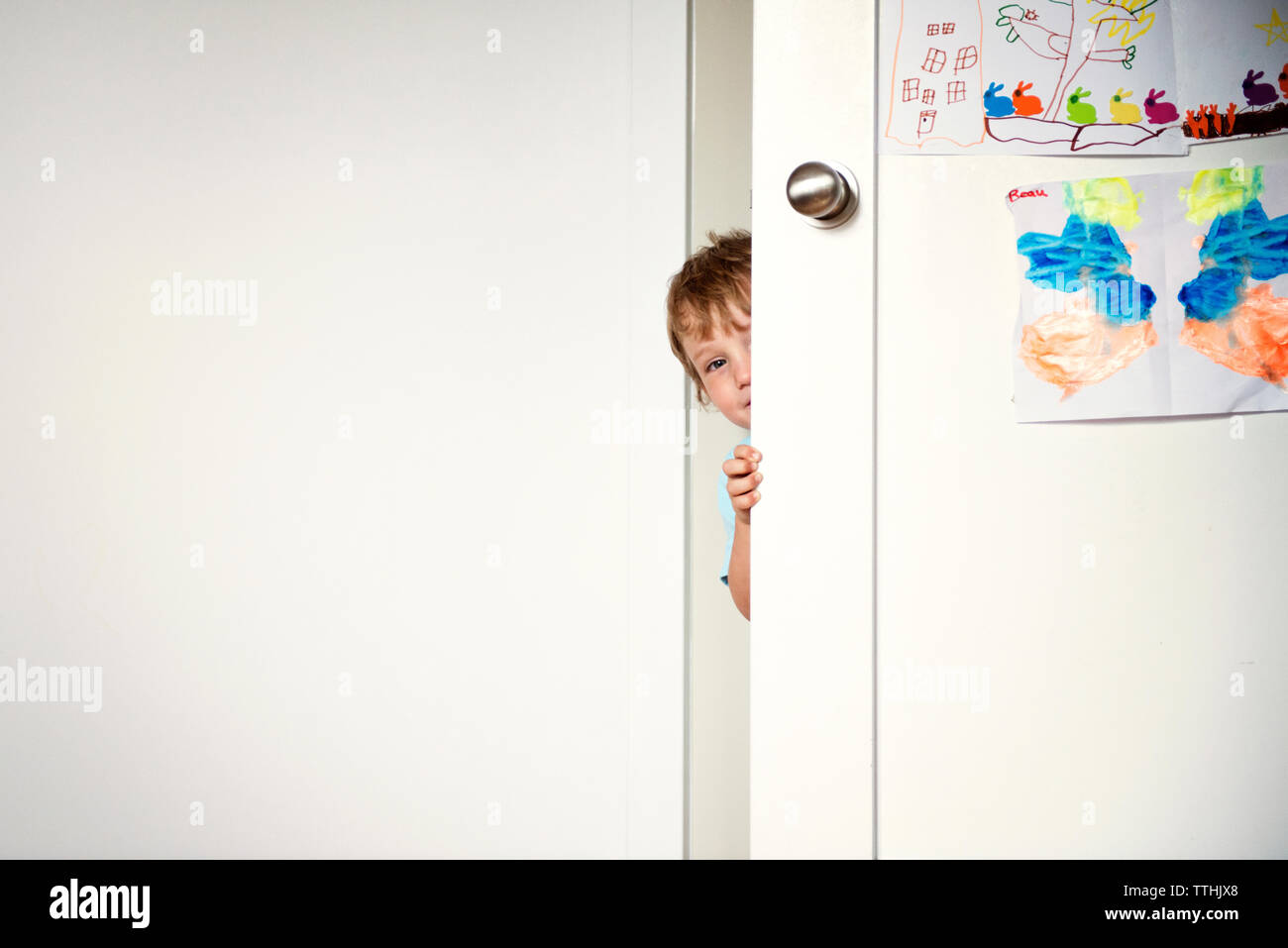 Portrait of boy behind door at home Stock Photo - Alamy