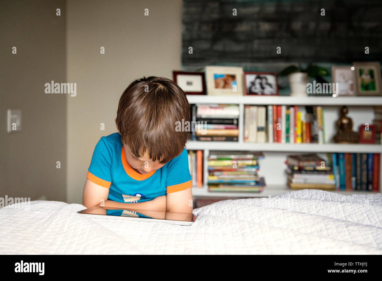 Boy using tablet computer while lying on bed at home Stock Photo - Alamy