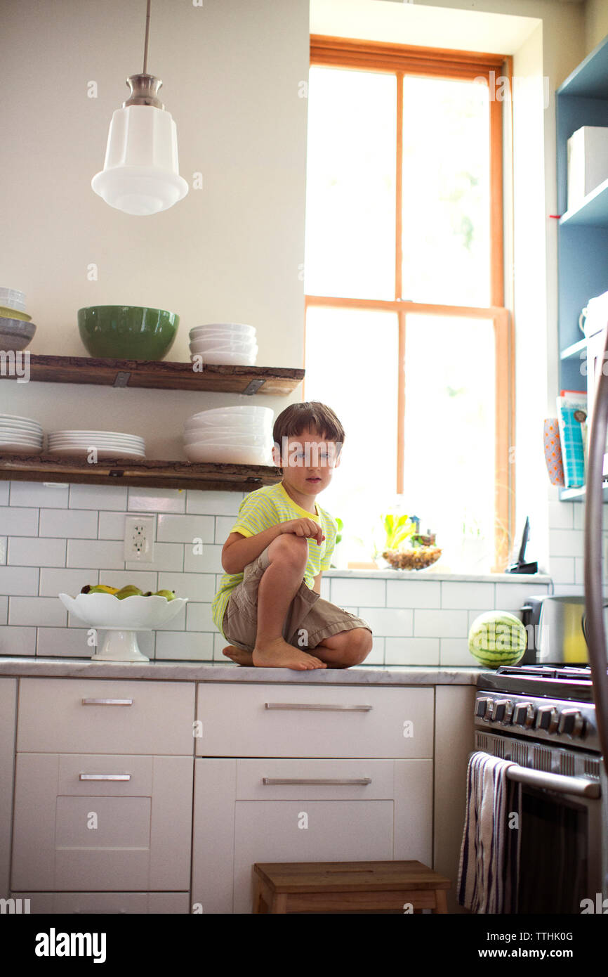 Portrait of boy sitting on kitchen counter Stock Photo - Alamy