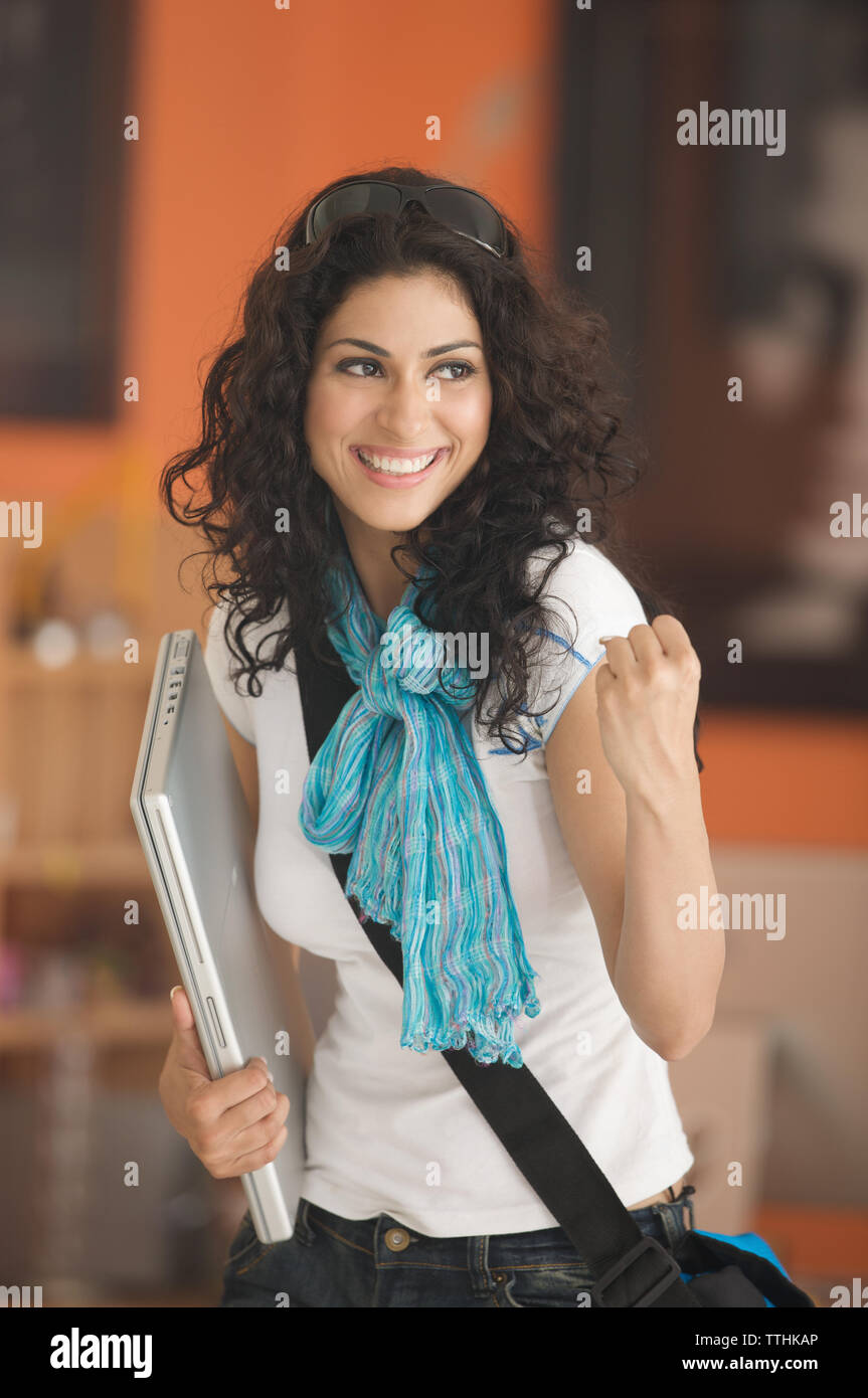 College student carrying a laptop and smiling Stock Photo - Alamy