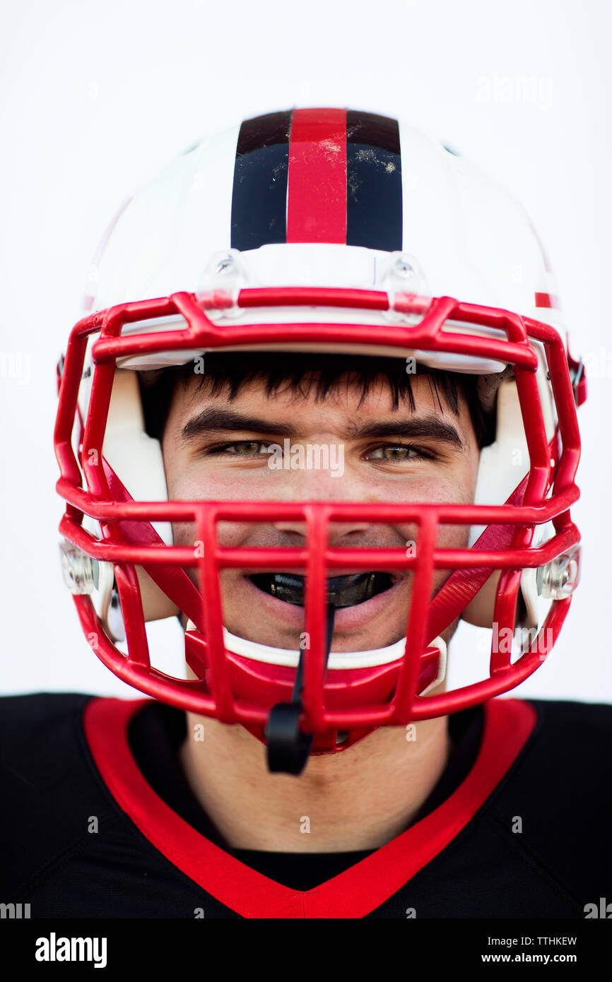 Portrait of smiling American football player with helmet against white ...