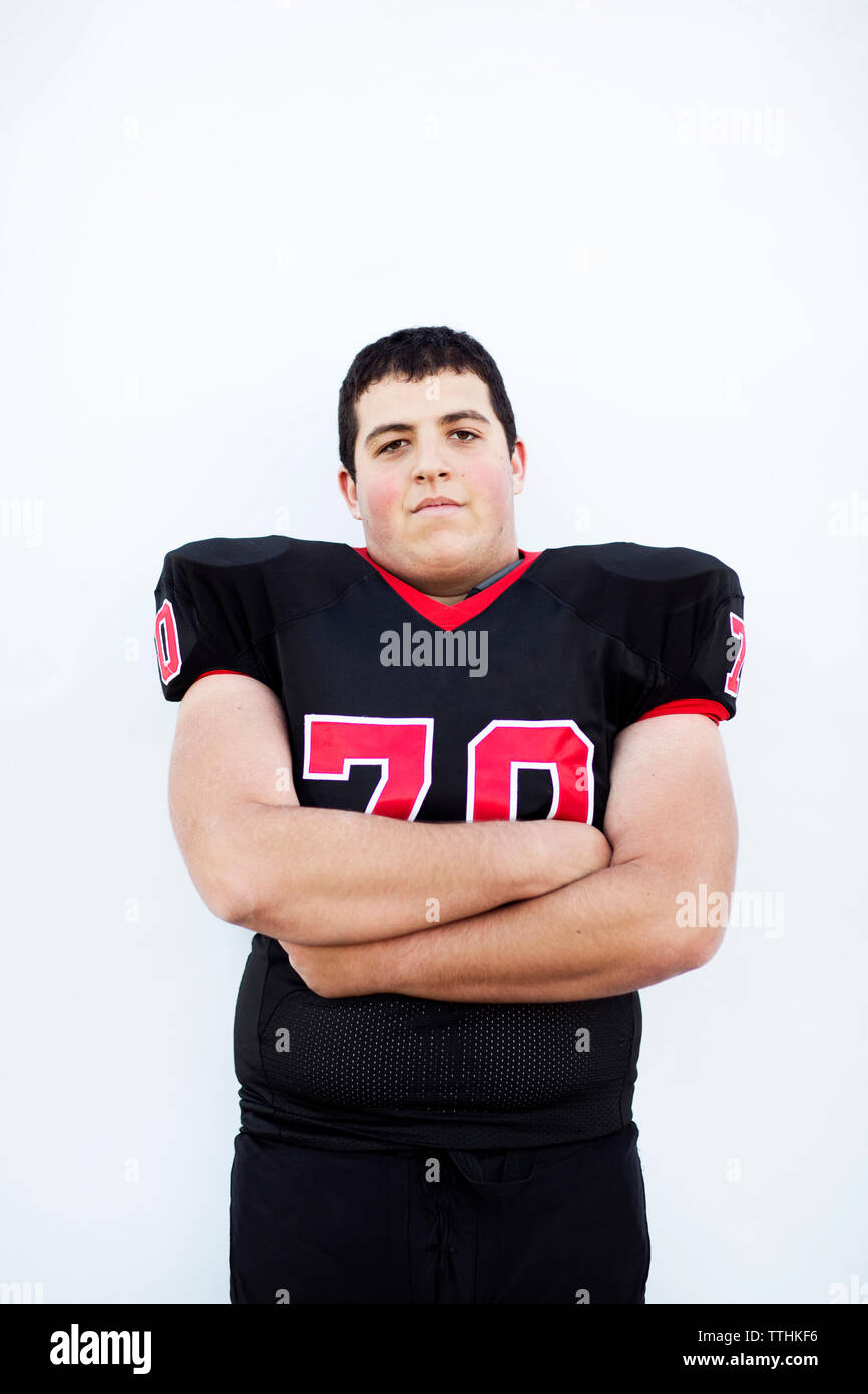 Portrait of confident American football player standing against white ...