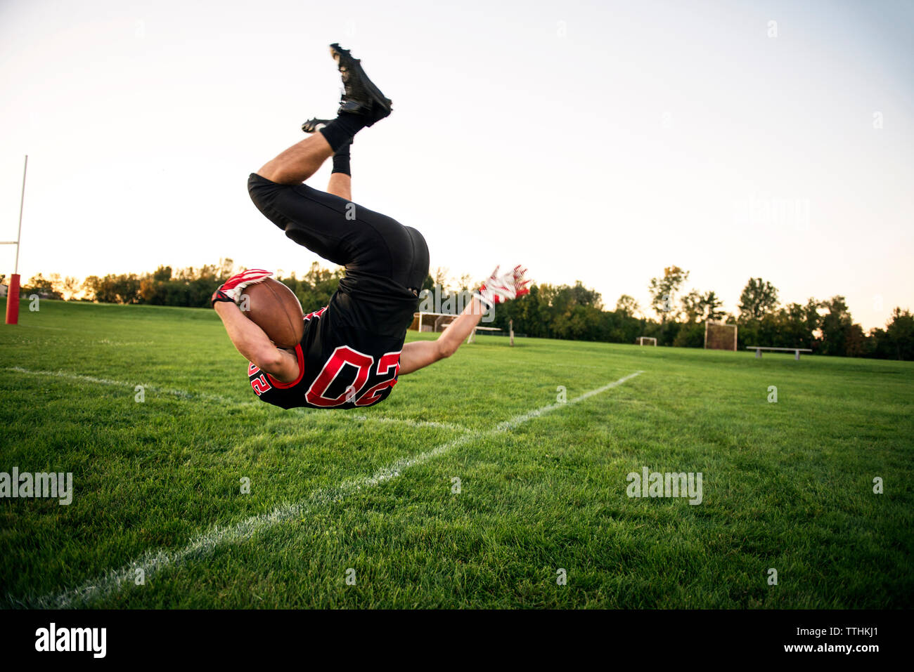 Boy jumping with American football on playing field Stock Photo - Alamy