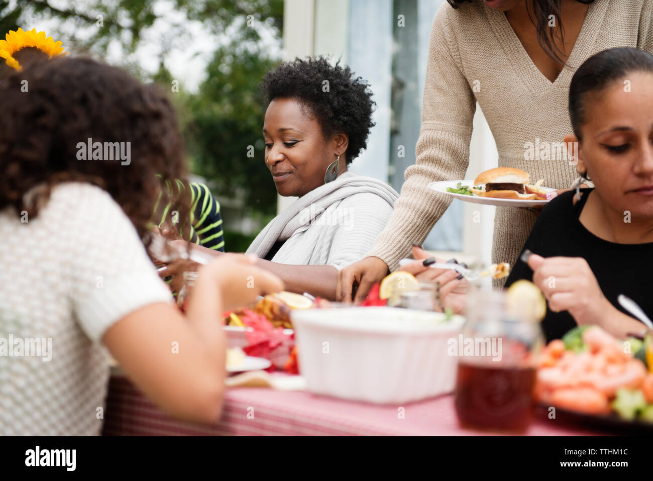 Family and friends eating food on picnic table at backyard Stock Photo ...