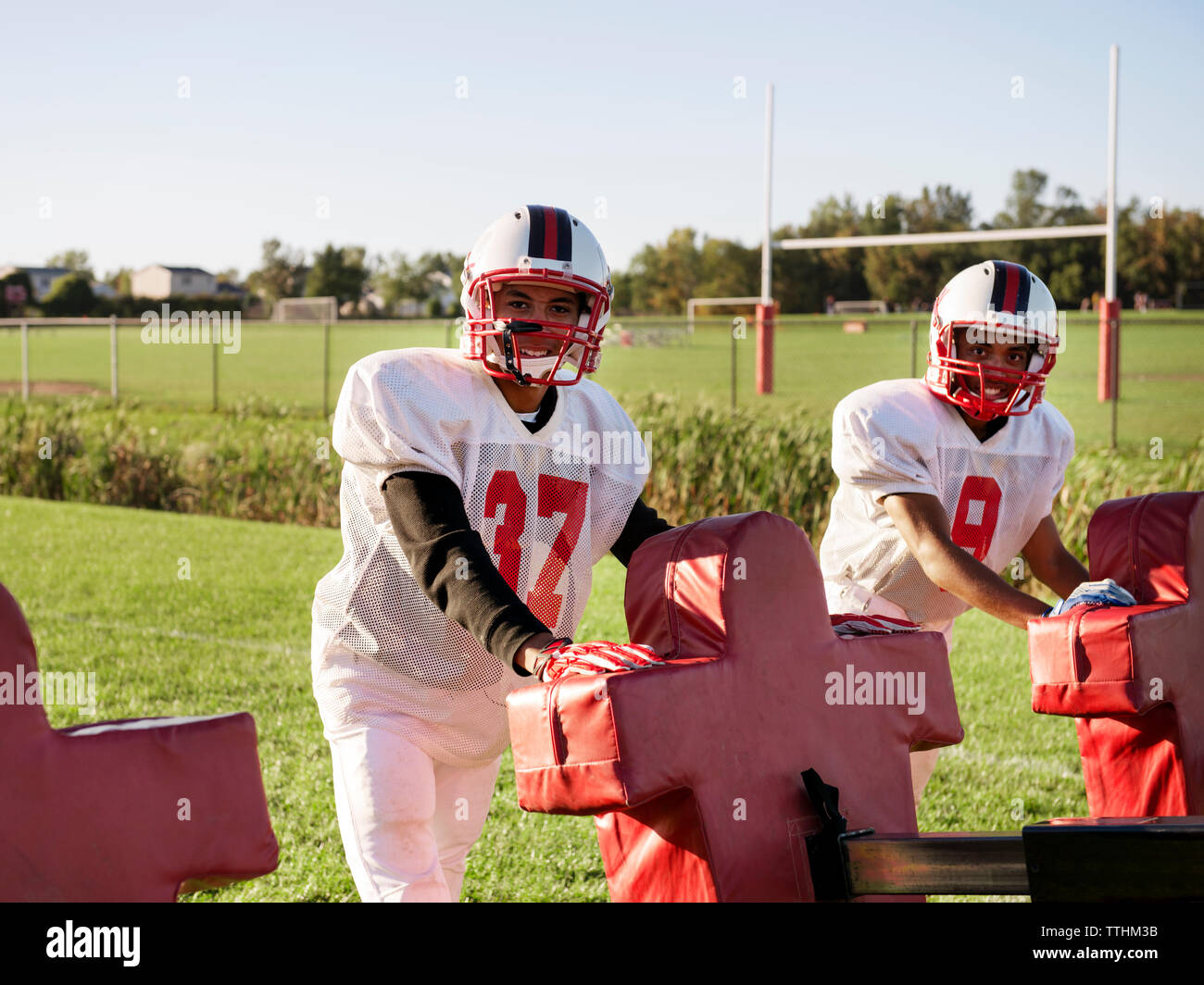 Portrait of American football players training on sled at field Stock ...