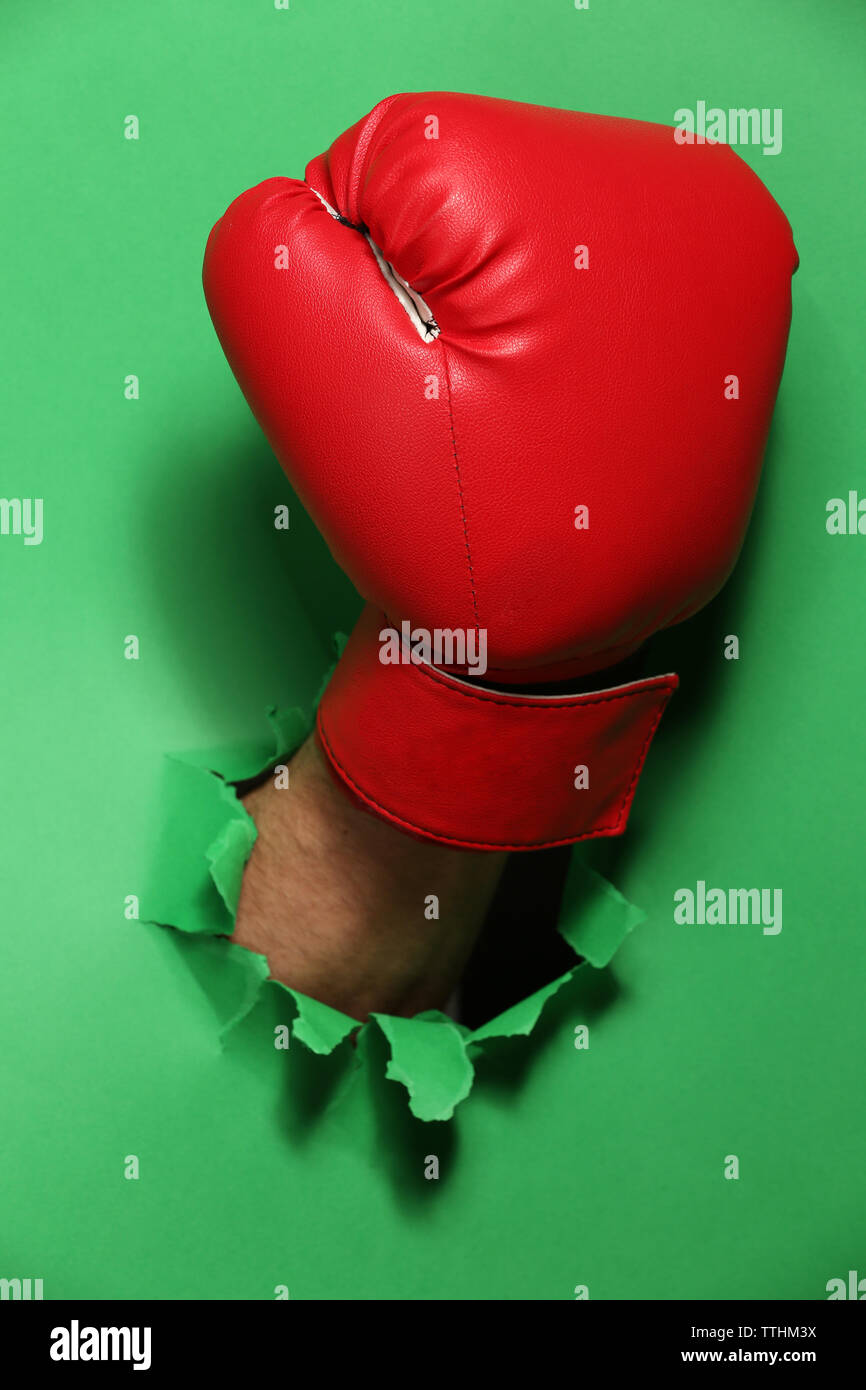 Male hand in boxing glove through green paper Stock Photo - Alamy