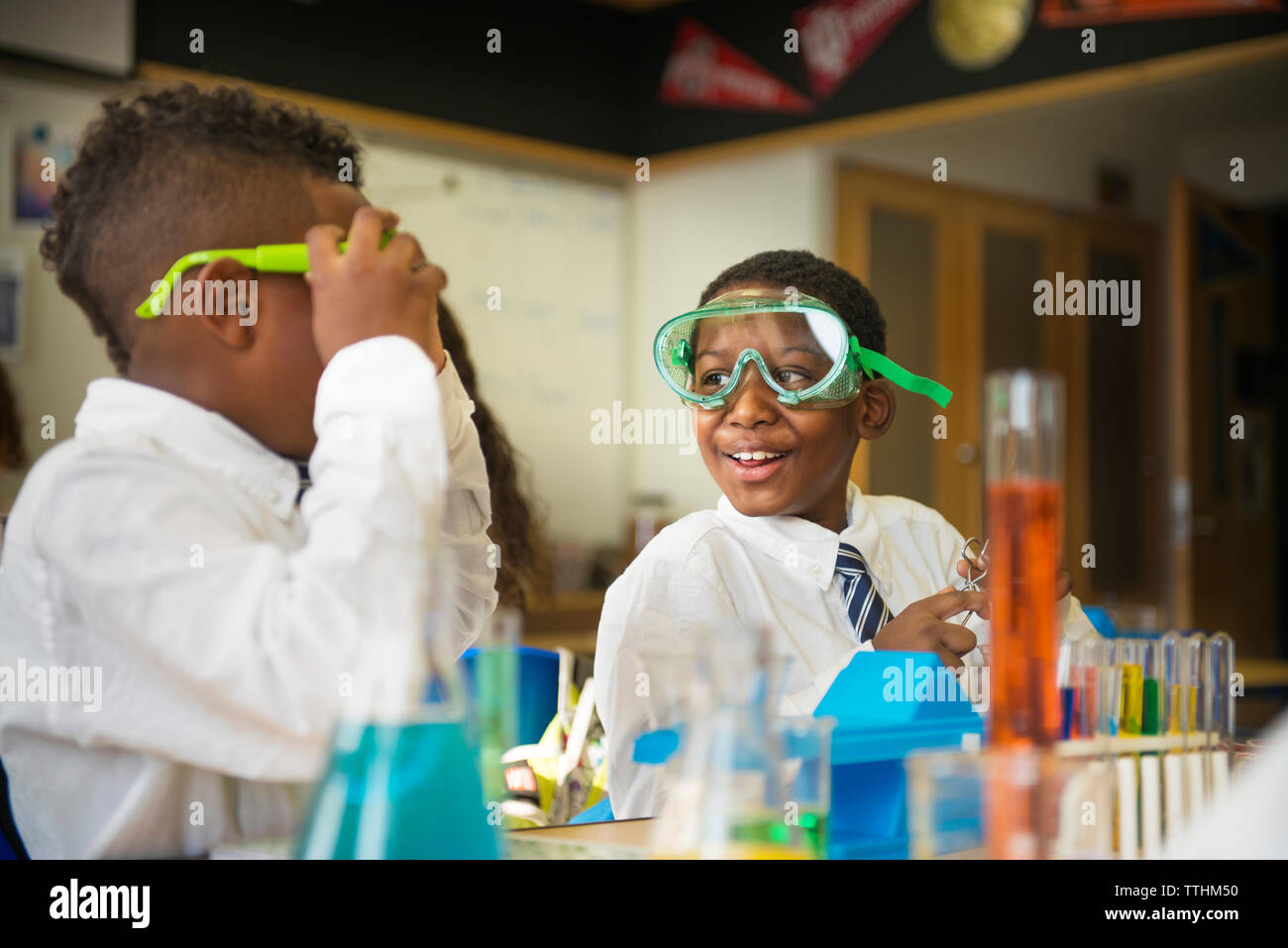 Happy boy wearing protective eyewear while looking at friend in ...