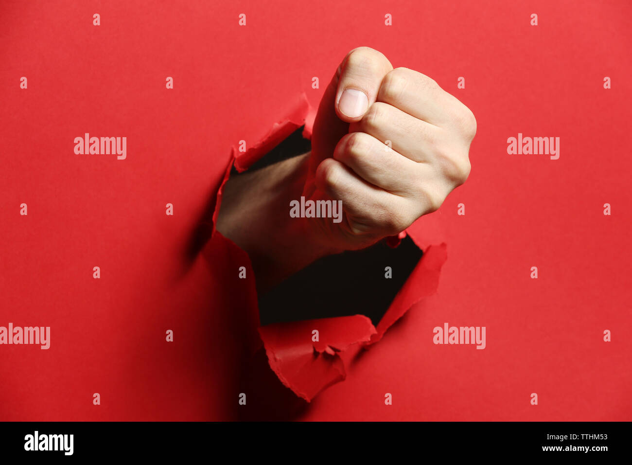 Male fist punching through red paper Stock Photo - Alamy