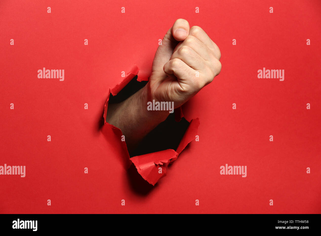 Male fist punching through red paper Stock Photo - Alamy