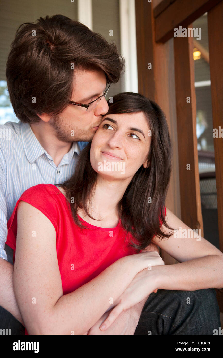 Man kissing girlfriend while sitting by railing Stock Photo - Alamy