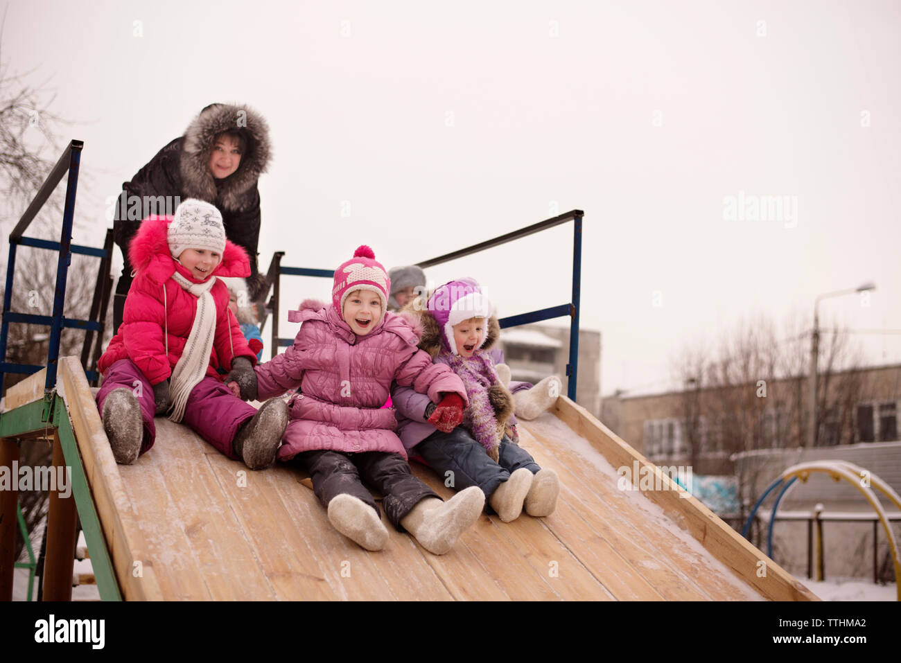 Low angle view of woman playing with children on slide at playground in ...