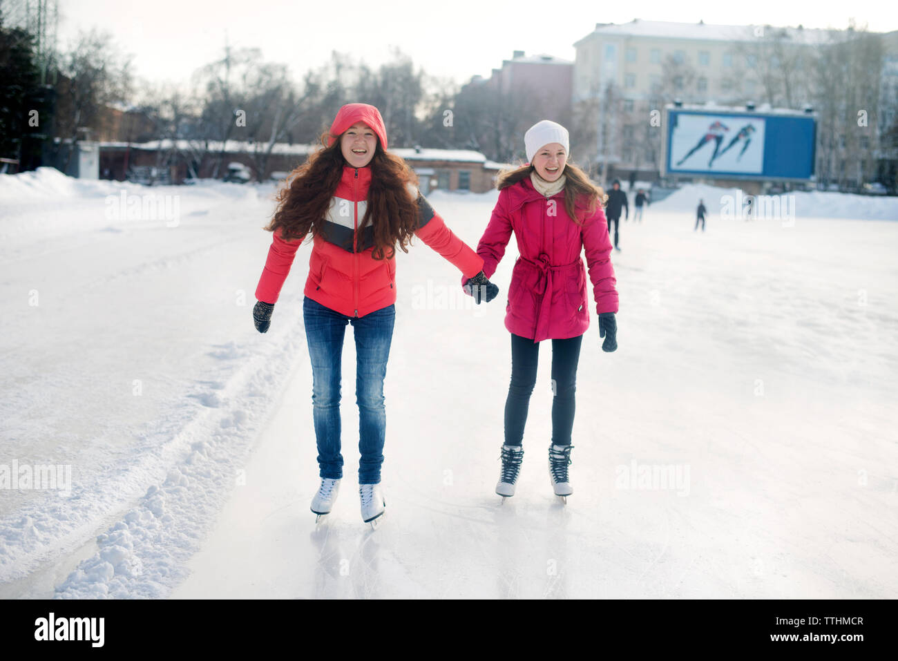 Happy friends ice-skating in park Stock Photo - Alamy