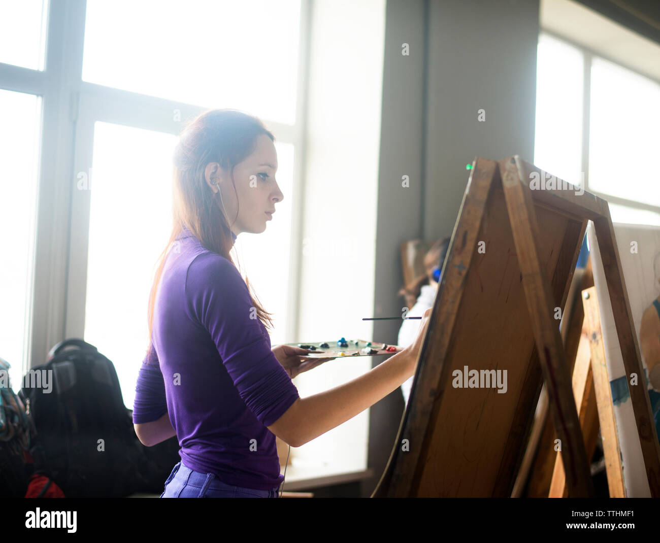 Woman painting while standing in art class Stock Photo - Alamy
