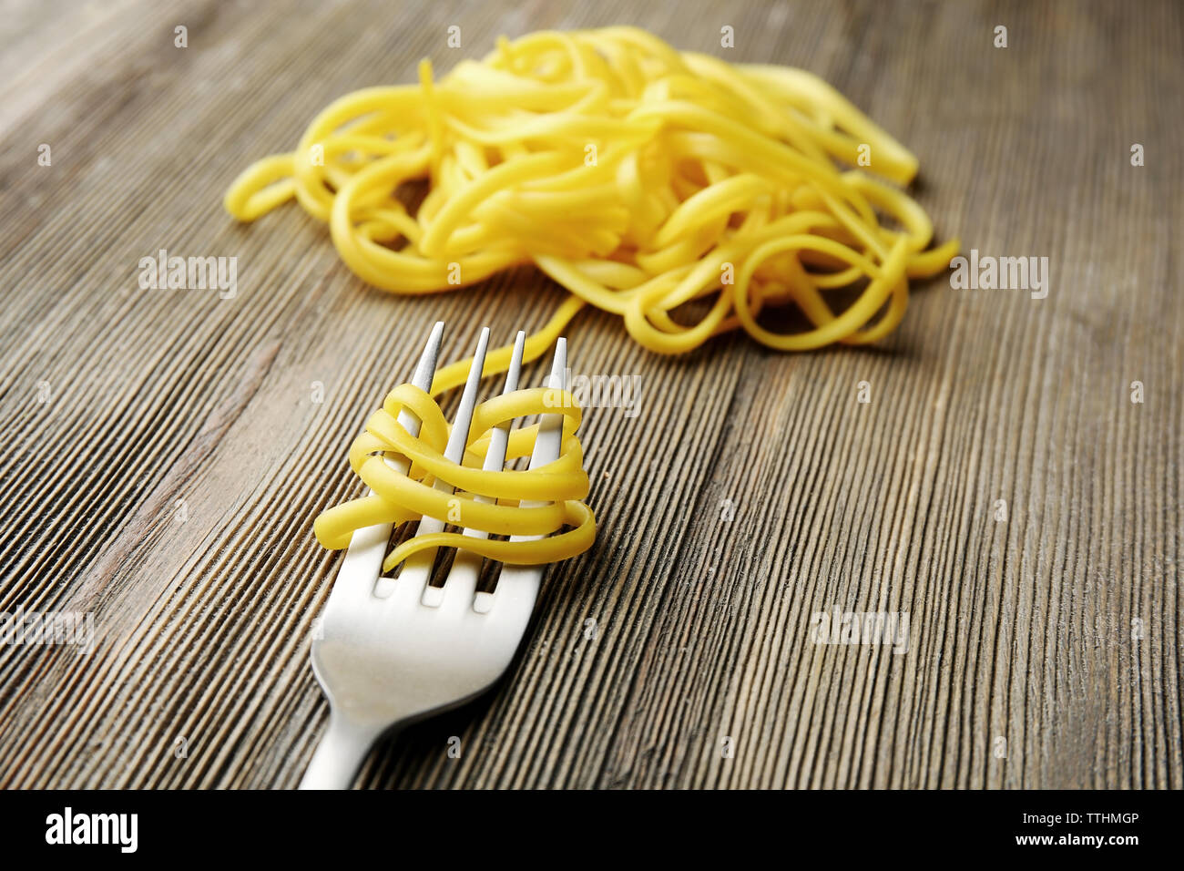 Fork with cooked pasta on wooden background Stock Photo - Alamy