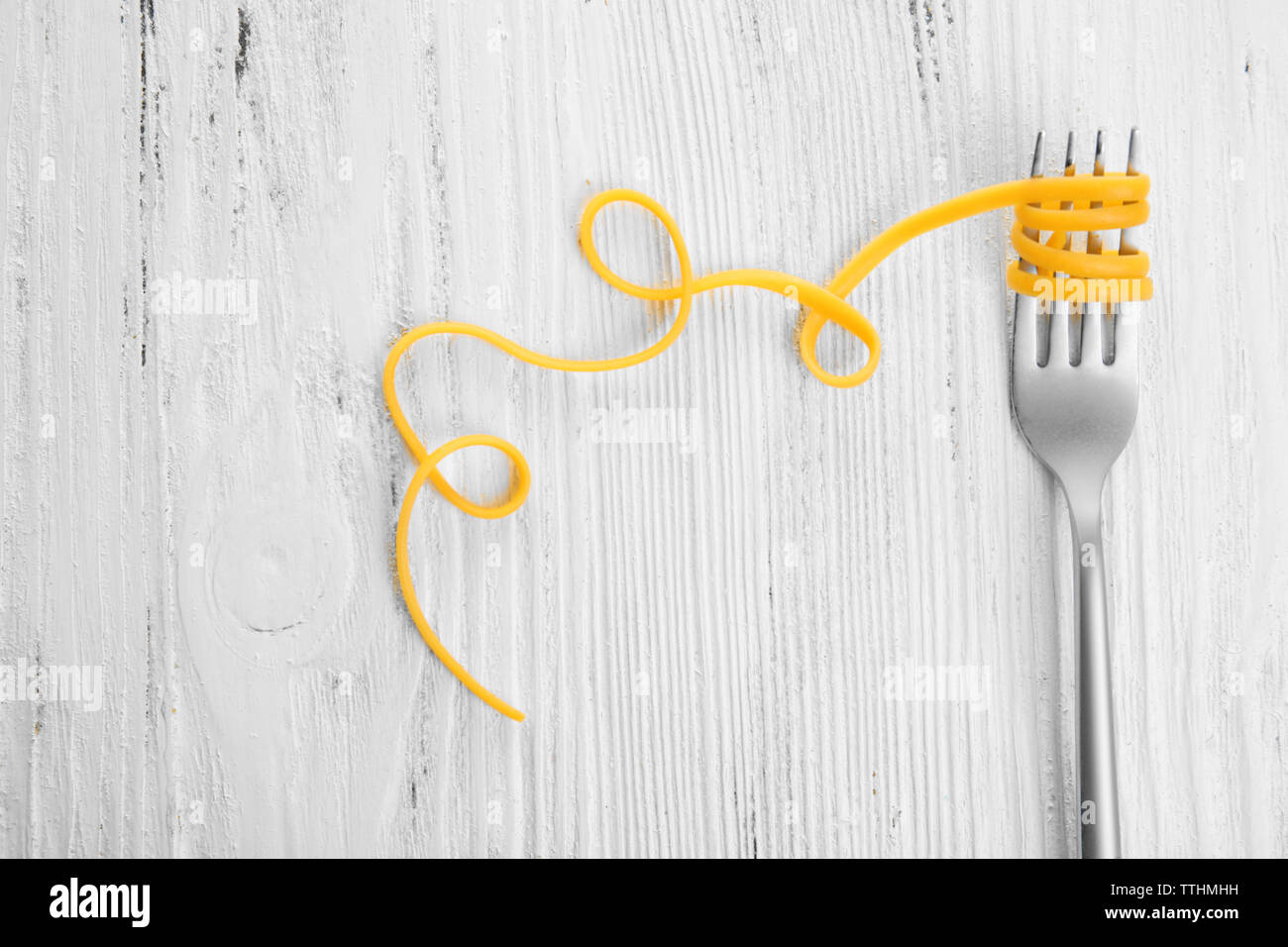 Swirls of pasta and fork on wooden background Stock Photo - Alamy