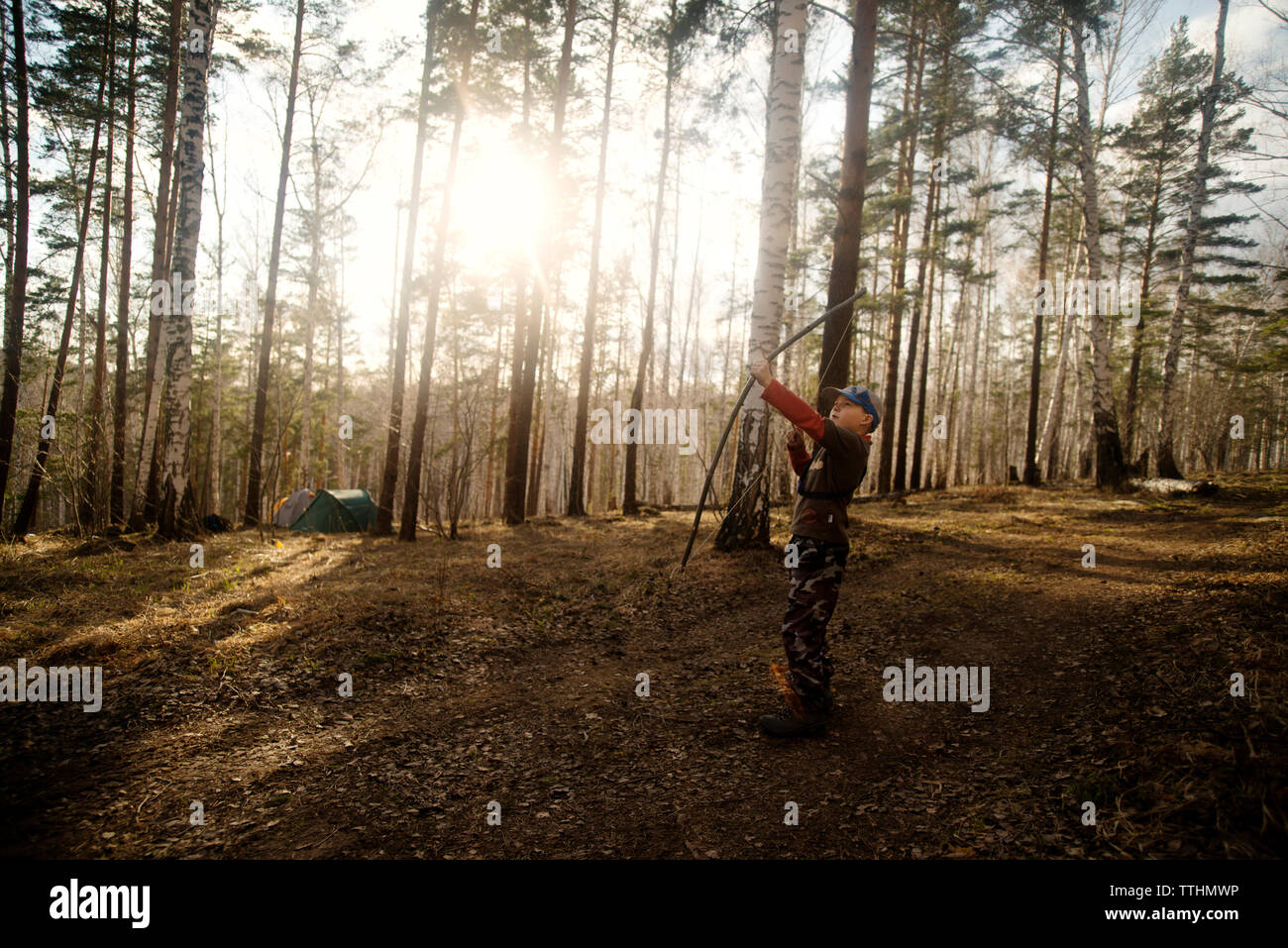Boy aiming at target while standing in forest Stock Photo - Alamy