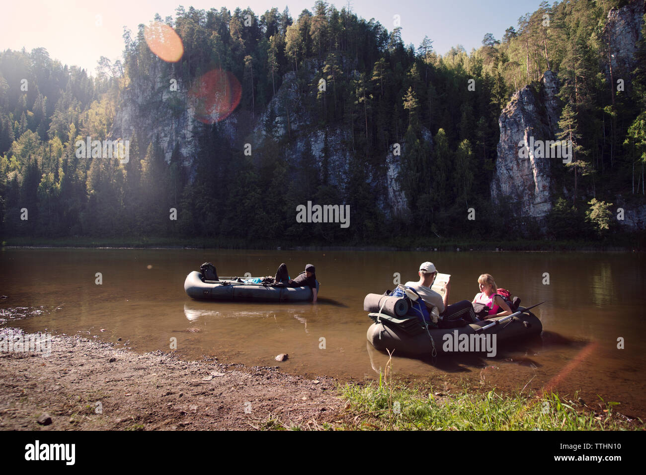 Friends sitting in raft on river against rock formations Stock Photo ...