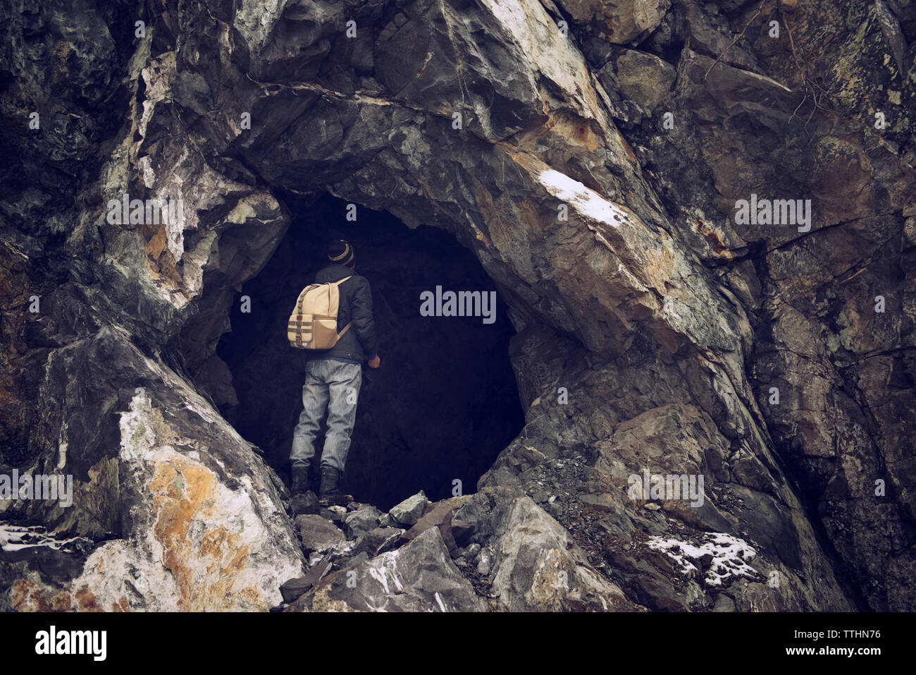 Hiker with backpack standing at cave Stock Photo - Alamy