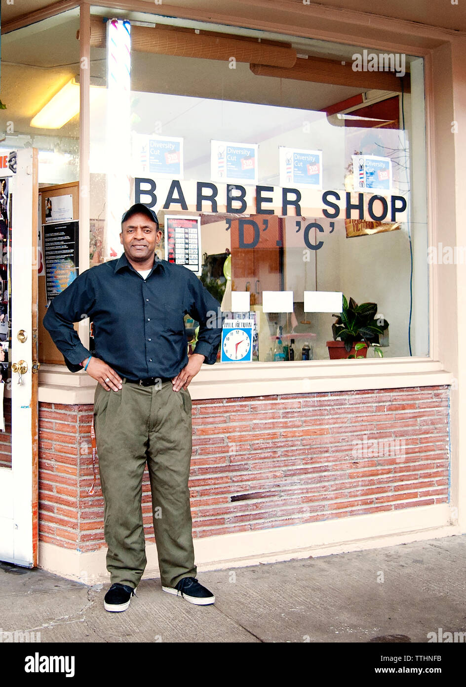 Male barber standing against hair salon Stock Photo - Alamy