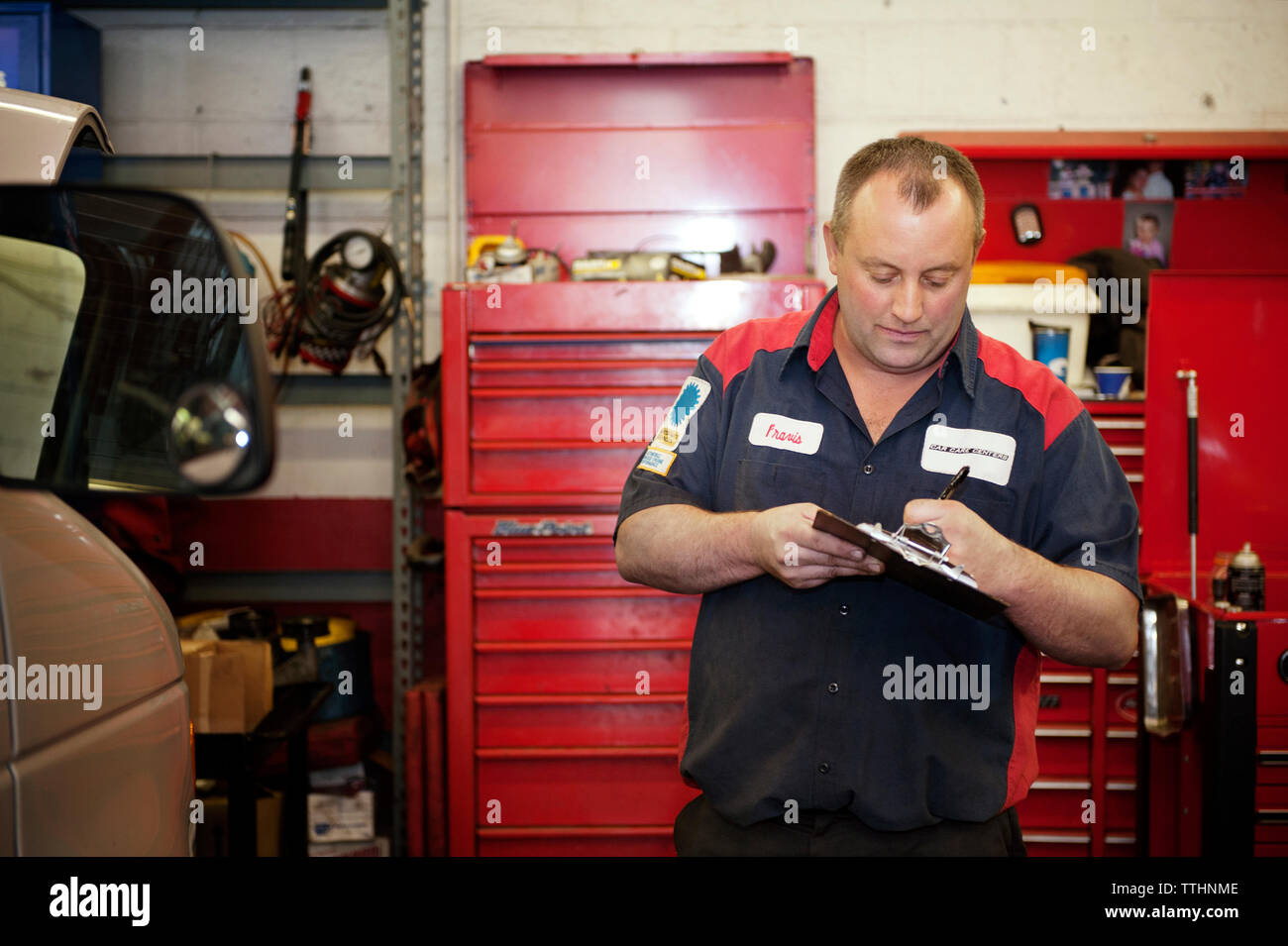 Mechanic writing while standing in garage Stock Photo - Alamy