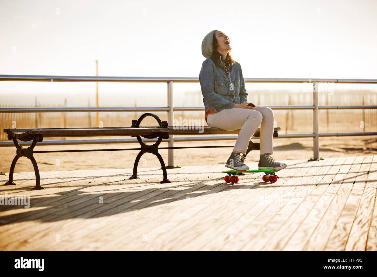 Woman laughing while sitting on bench at boardwalk Stock Photo - Alamy