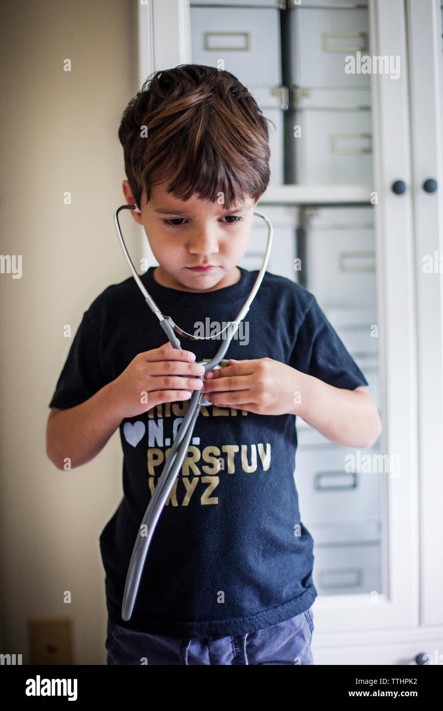 Boy using stethoscope while standing at home Stock Photo - Alamy