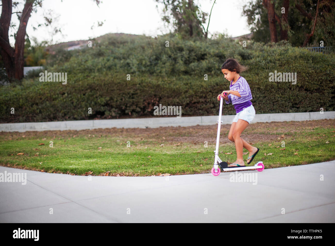 Side view of girl riding push scooter at park Stock Photo - Alamy