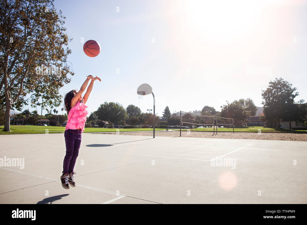 Girl jumping while throwing basketball on court Stock Photo - Alamy