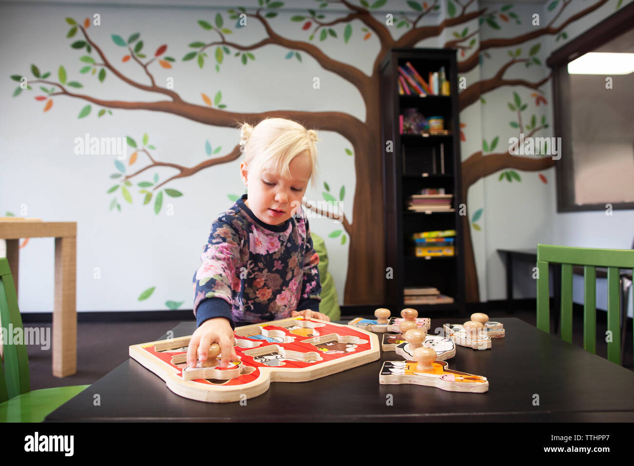 Girl playing knob puzzle at table in preschool Stock Photo - Alamy