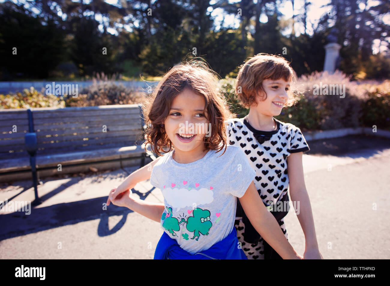Cheerful sisters holding hand while playing in park Stock Photo - Alamy