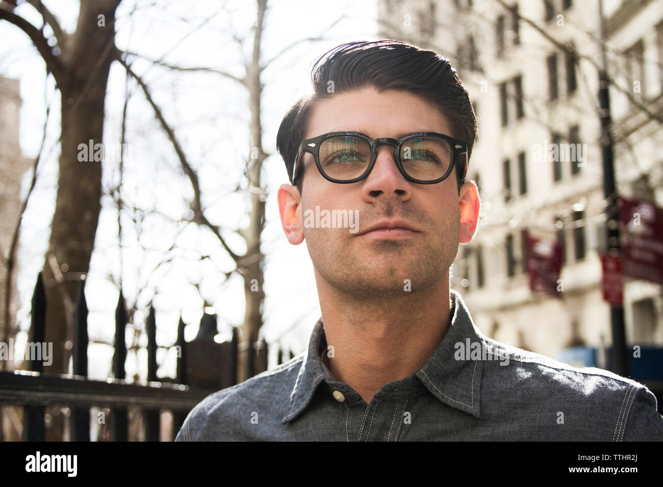 Thoughtful man looking away while standing on street Stock Photo - Alamy