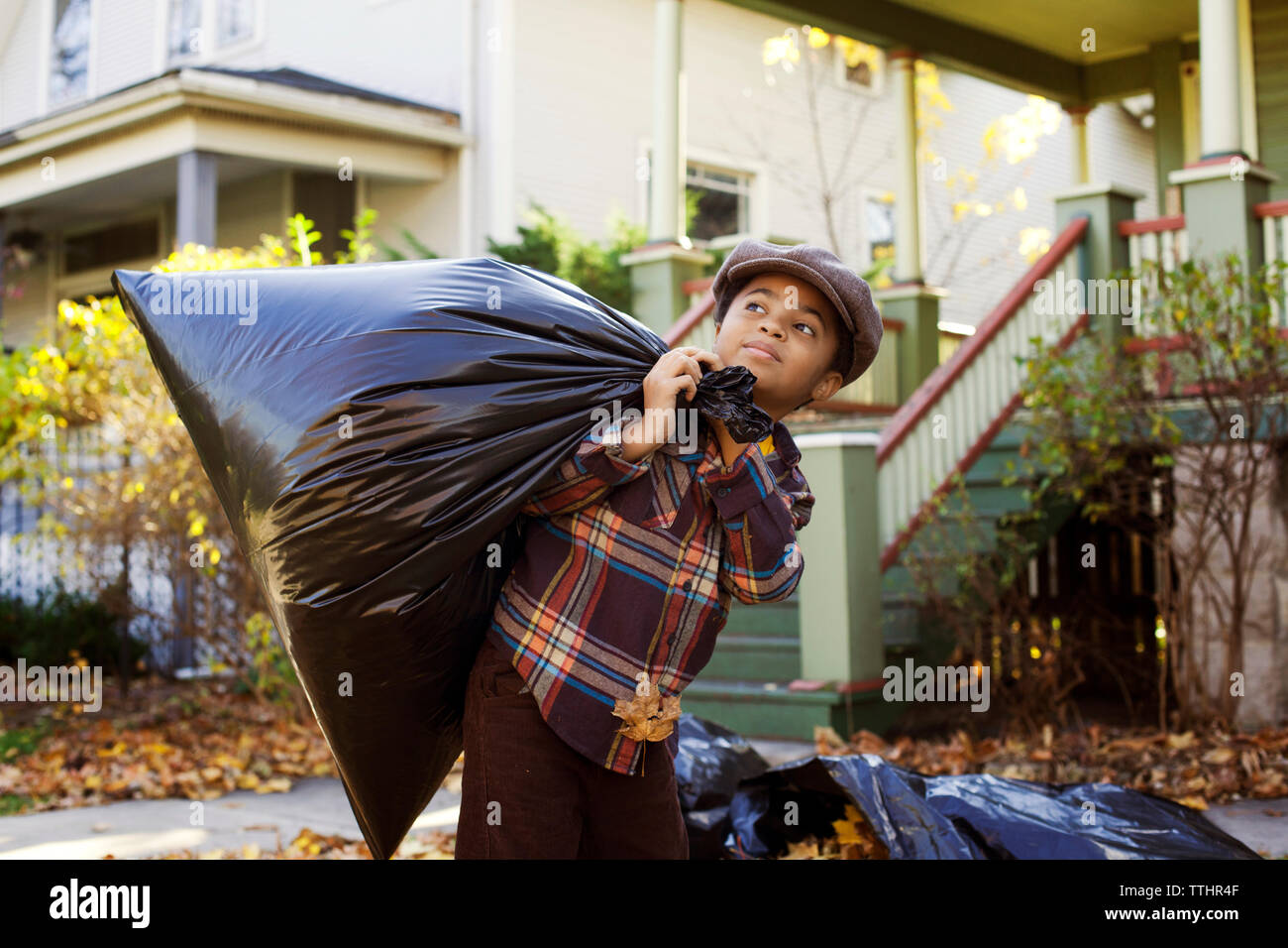 Boy looking away while carrying garbage bag at yard Stock Photo - Alamy