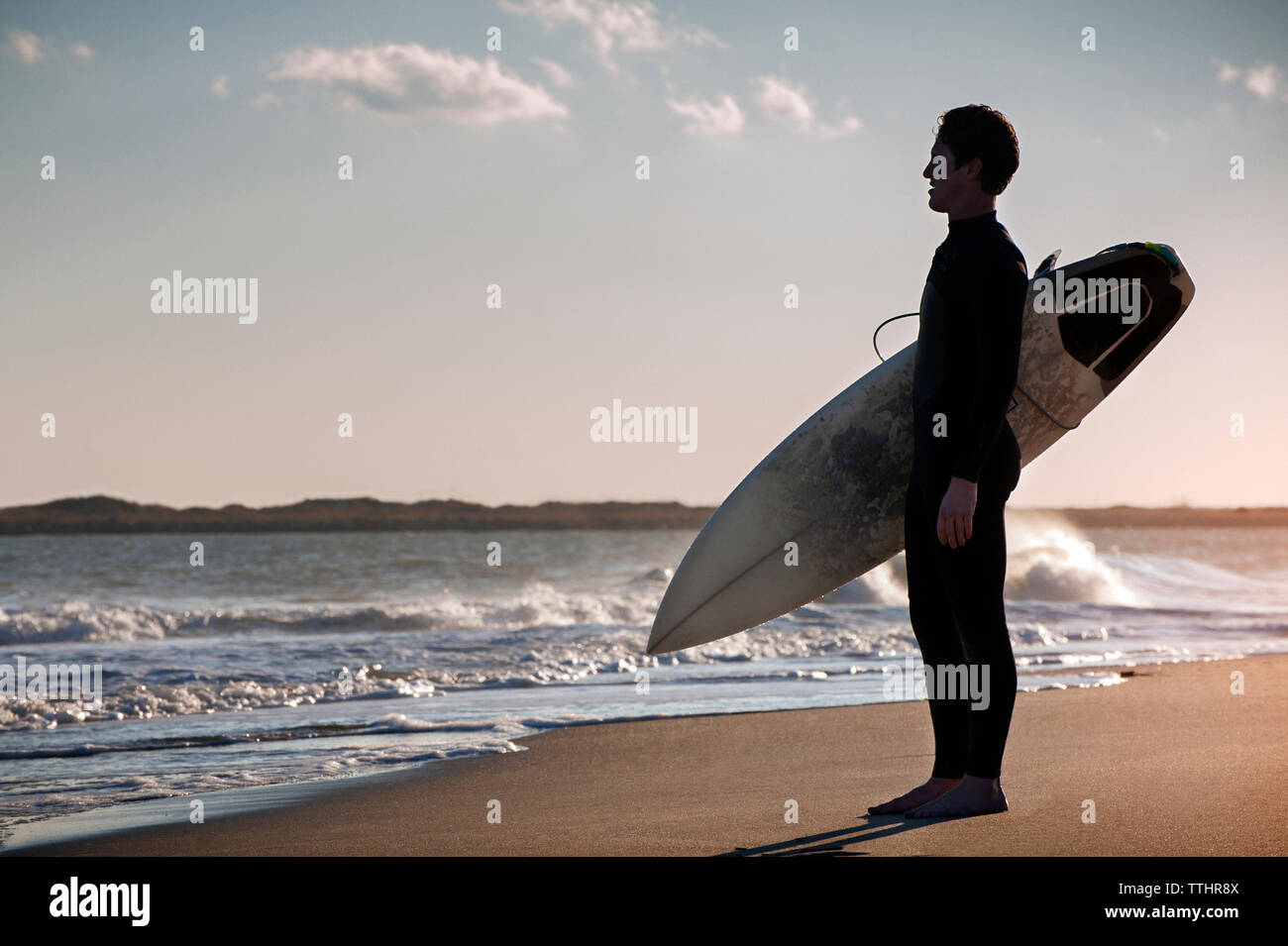 Side view of surfer carrying surfboard while standing on shore Stock ...