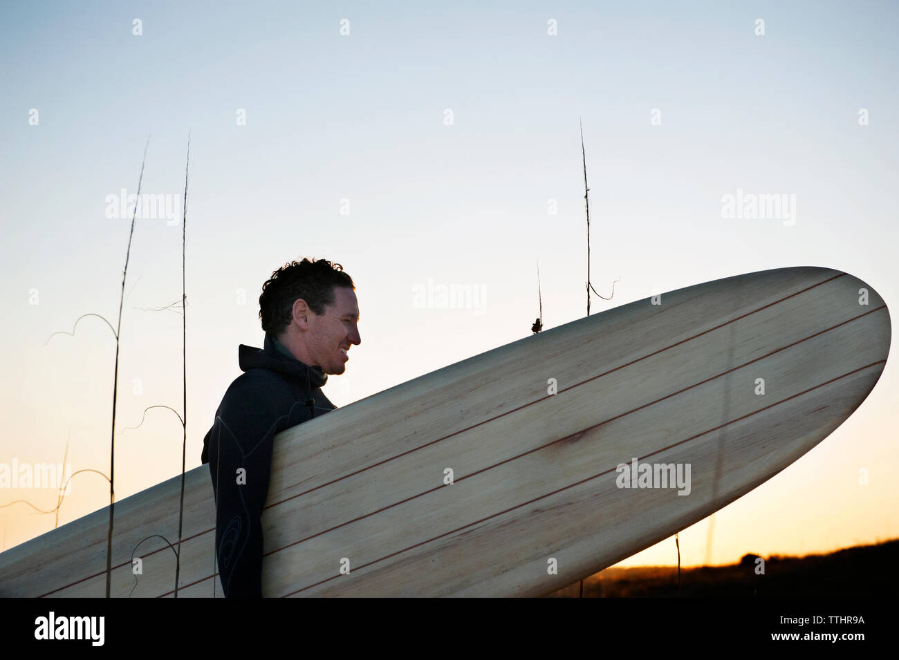 Side view of surfer carrying surfboard against clear sky Stock Photo ...