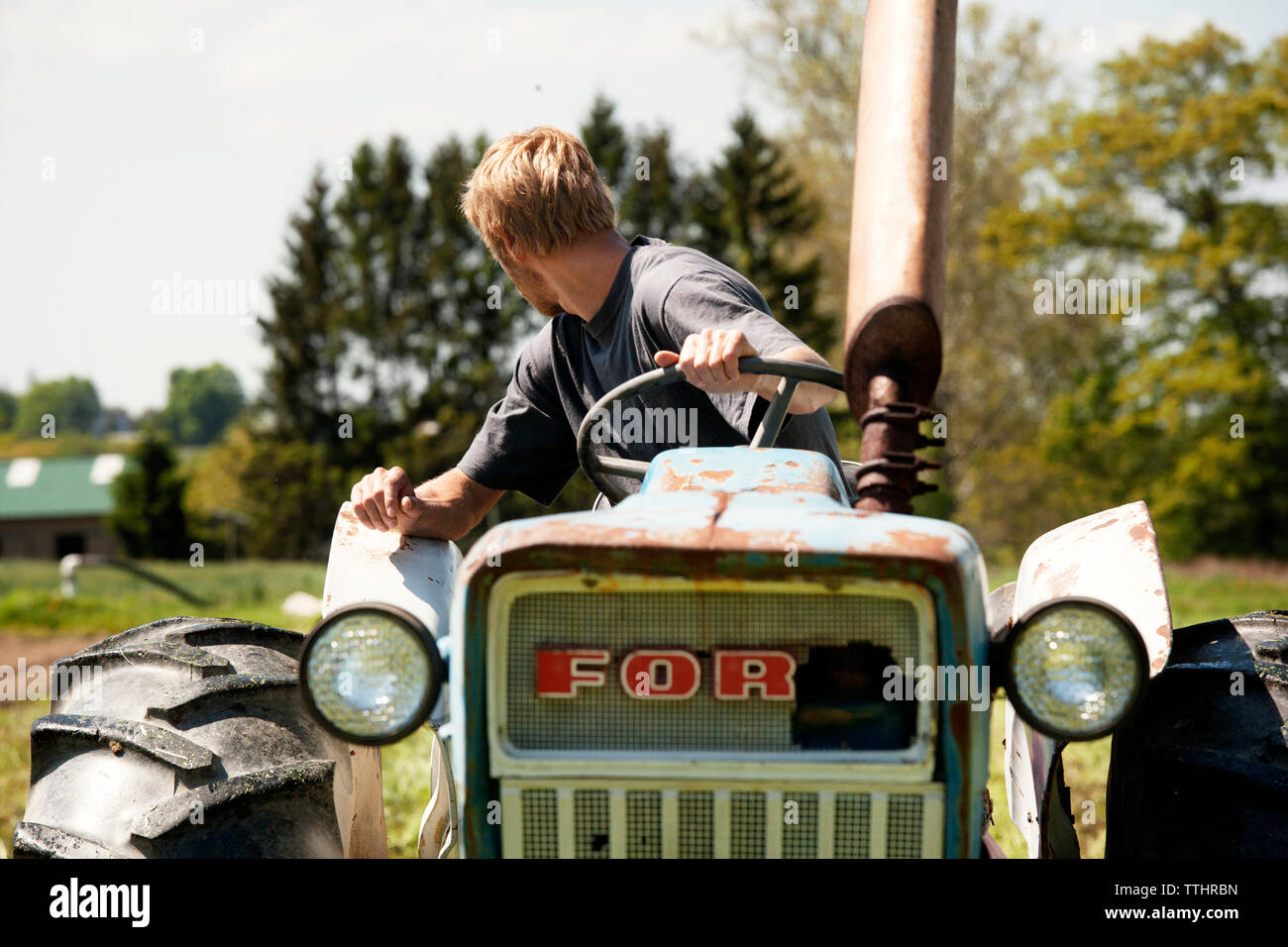 Farmer riding tractor on agriculture field Stock Photo - Alamy