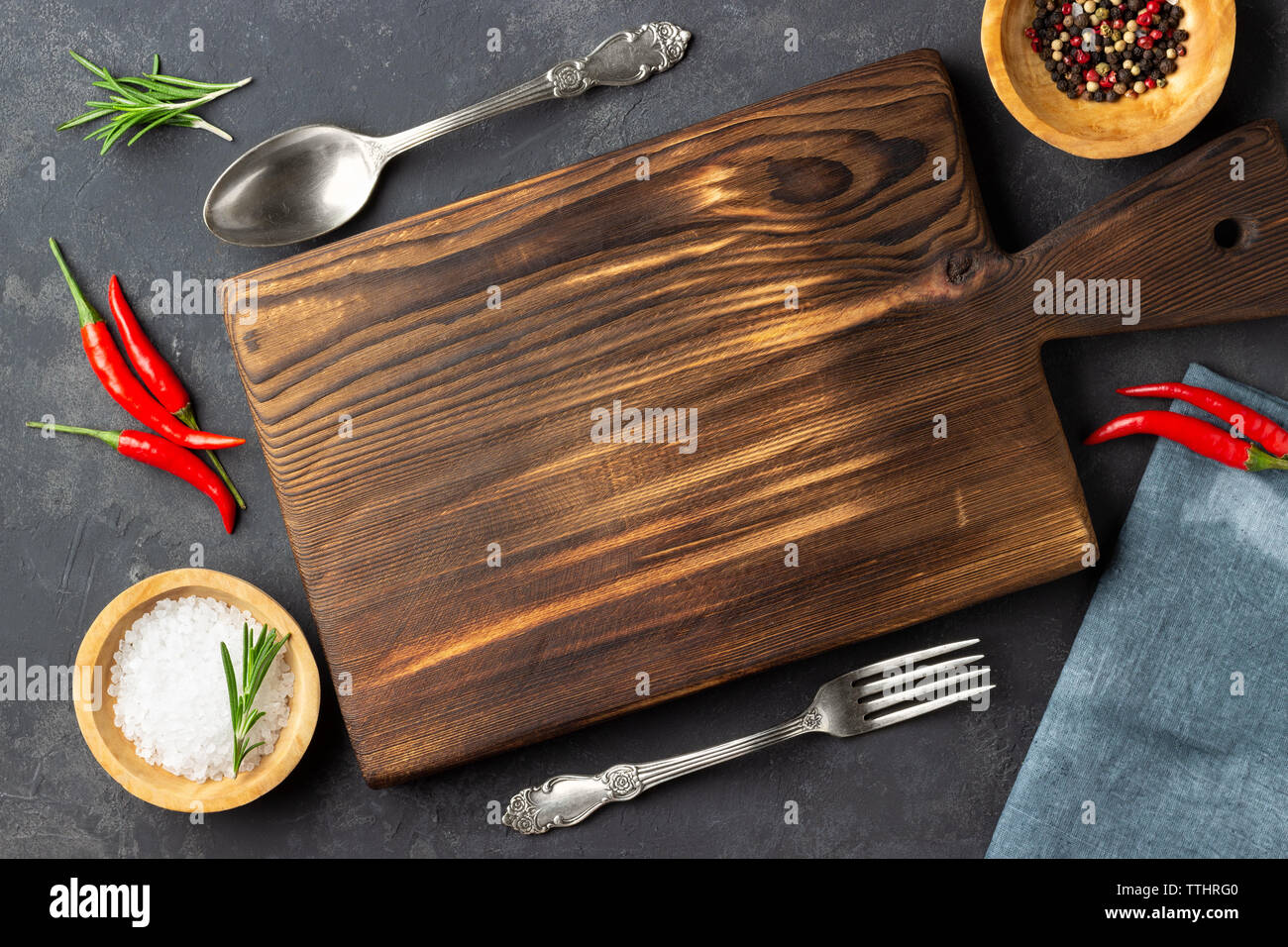 Cooking concept. Vintage cutting board with spices and cutlery on dark ...