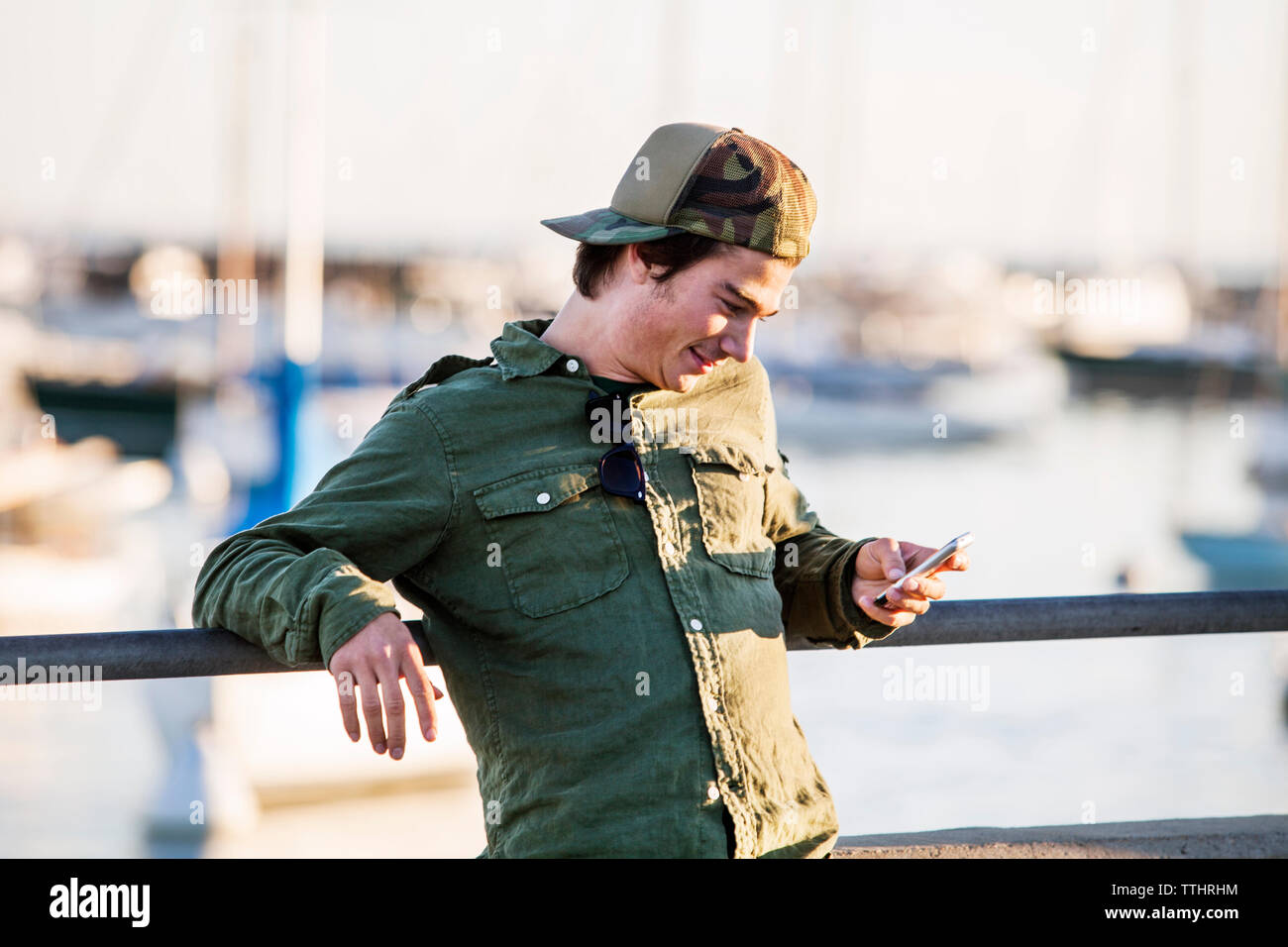 Man using mobile phone while leaning on railing Stock Photo - Alamy