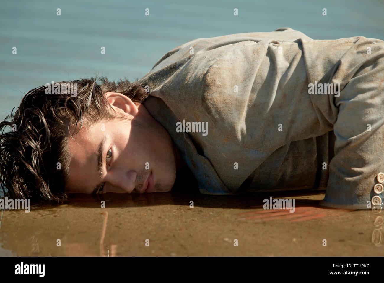 Man lying on shore at beach Stock Photo - Alamy