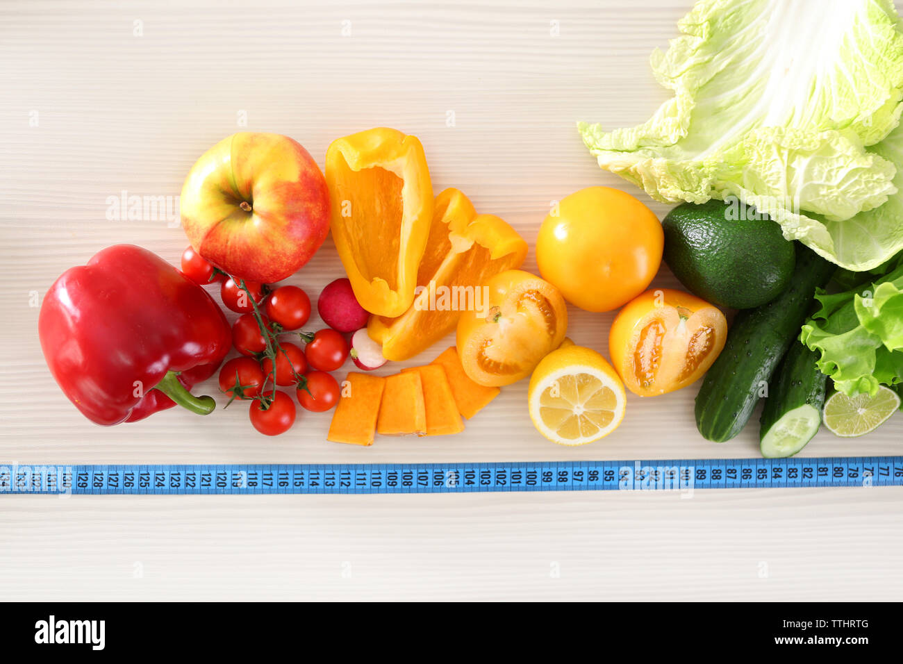 Fresh fruits and vegetables with measuring tape on wooden table, top ...