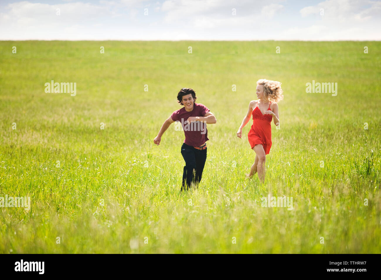 Couple running on grassy field Stock Photo - Alamy